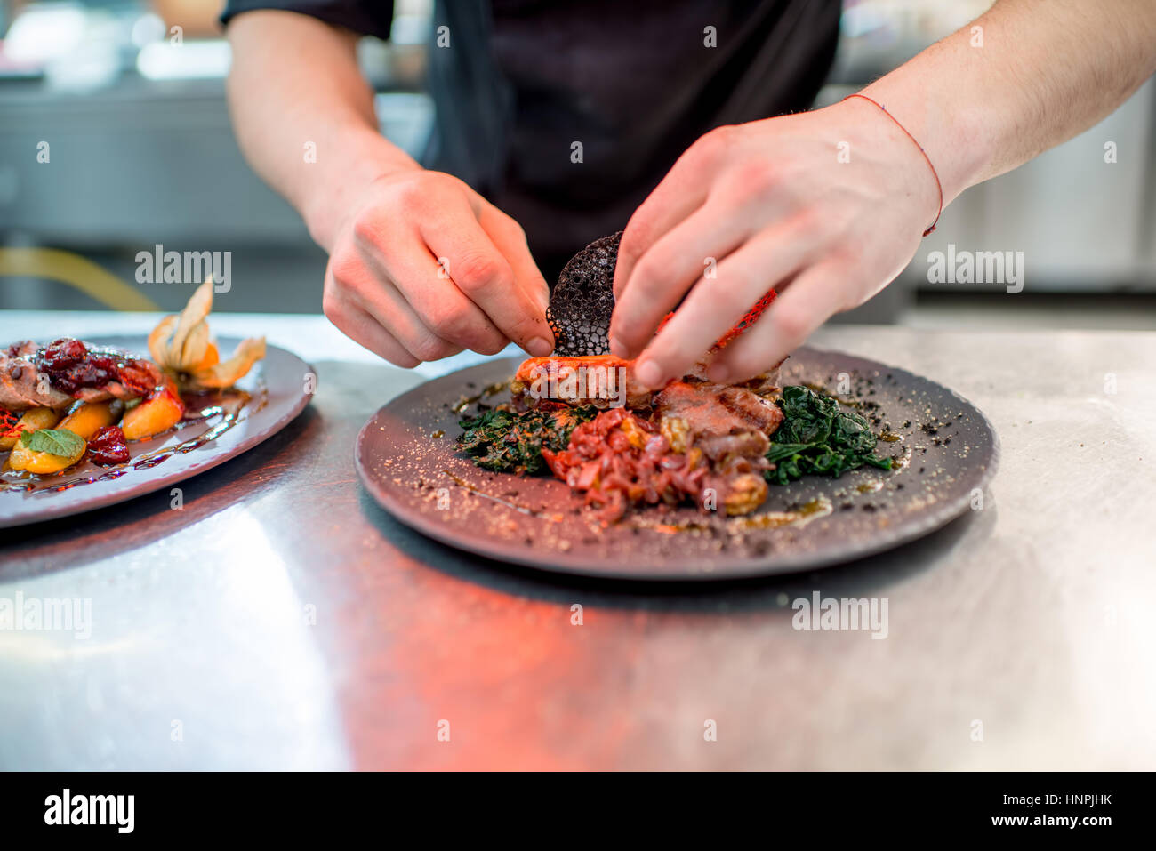 Finishing delicious restaurant dish with meat on the restaurant kitchen ...