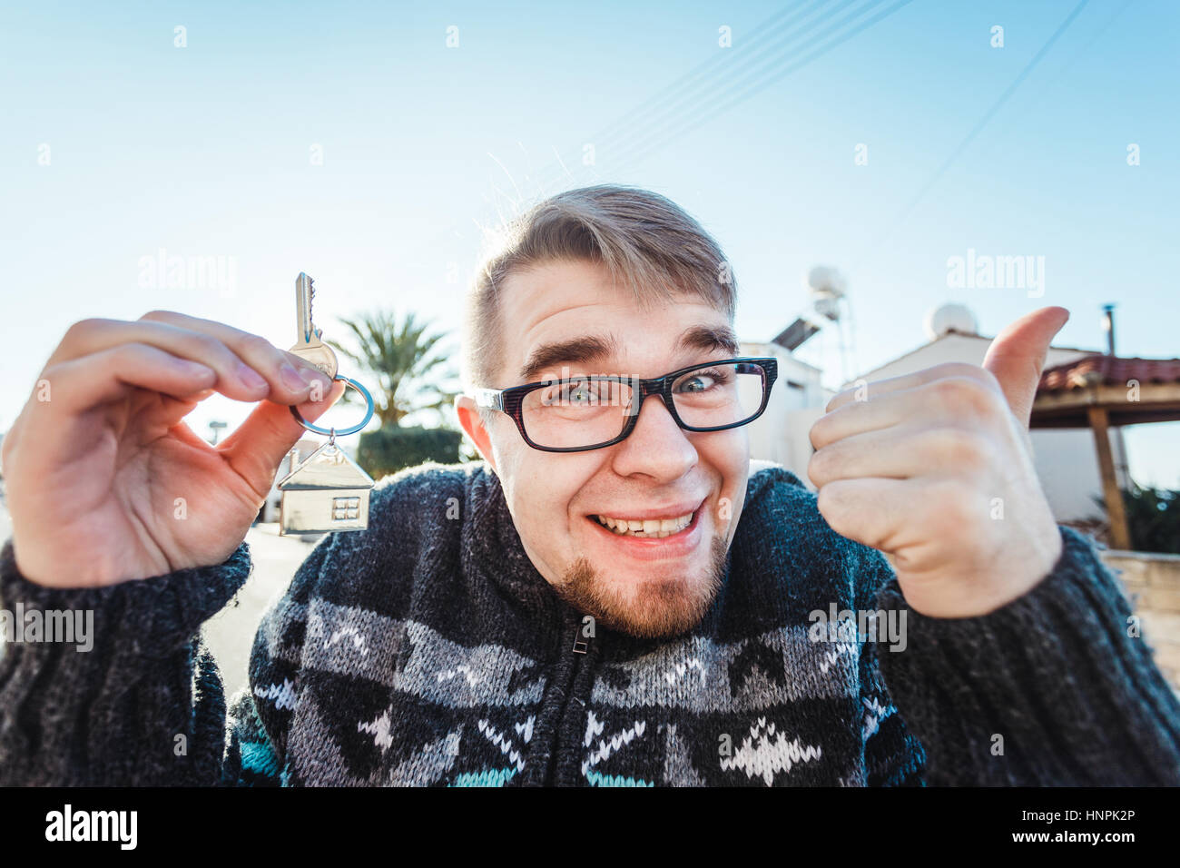 Happy funny man holds house keys on house shaped keychain in front of a ...