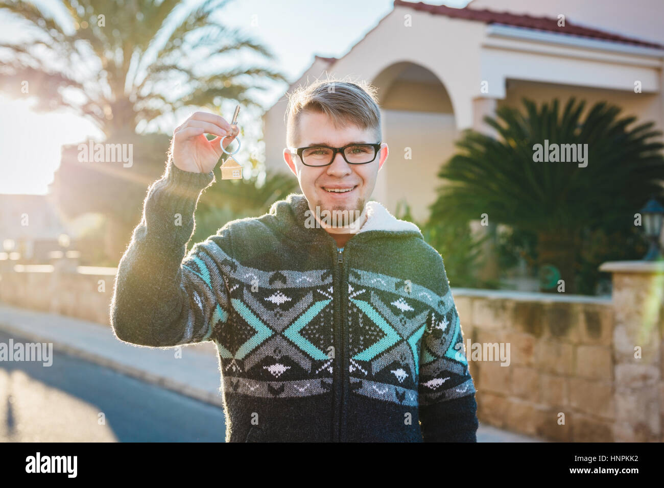 Happy funny man holds house keys on house shaped keychain in front of a ...