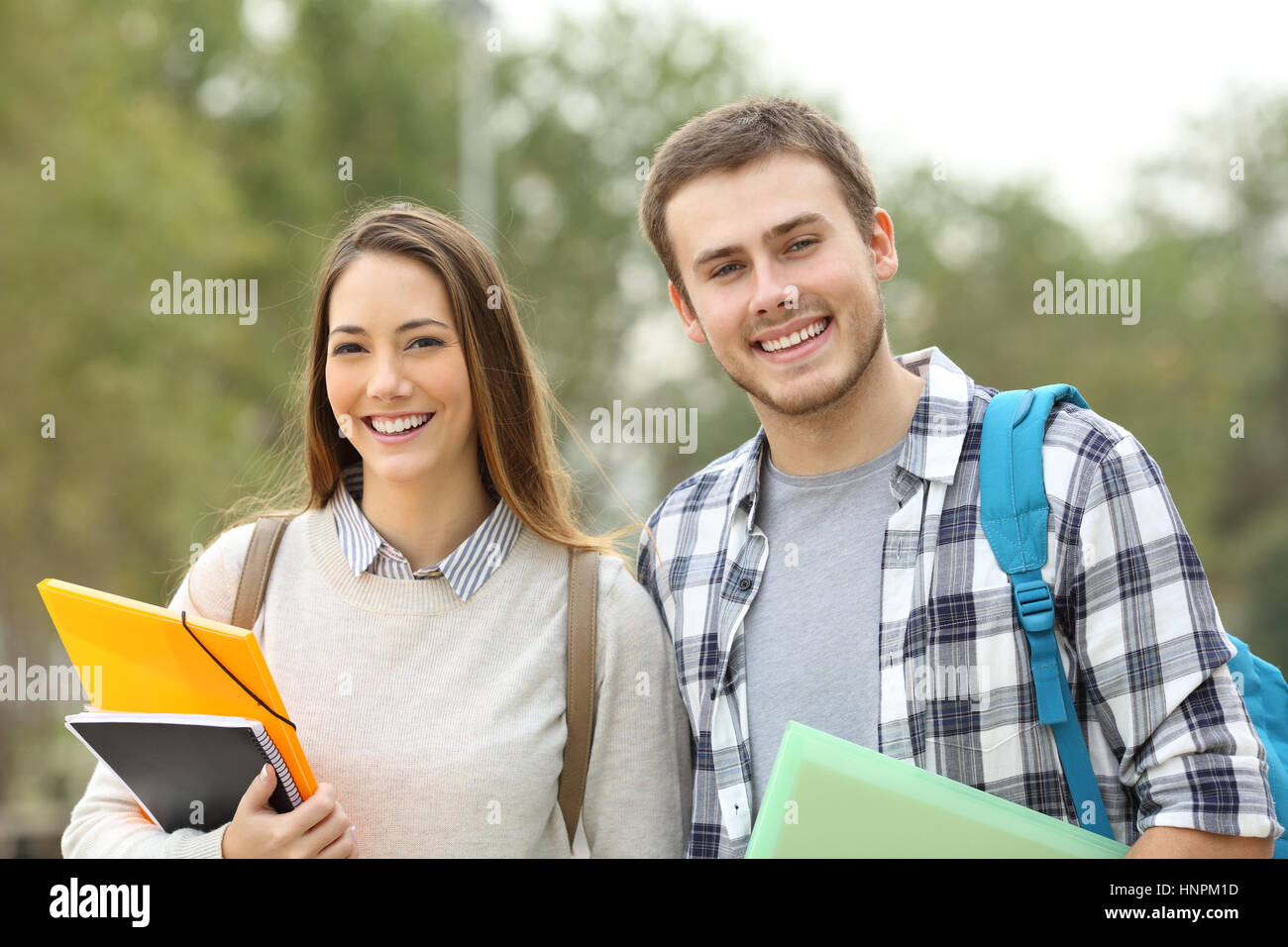 Two students posing looking at you outdoors in an university campus ...