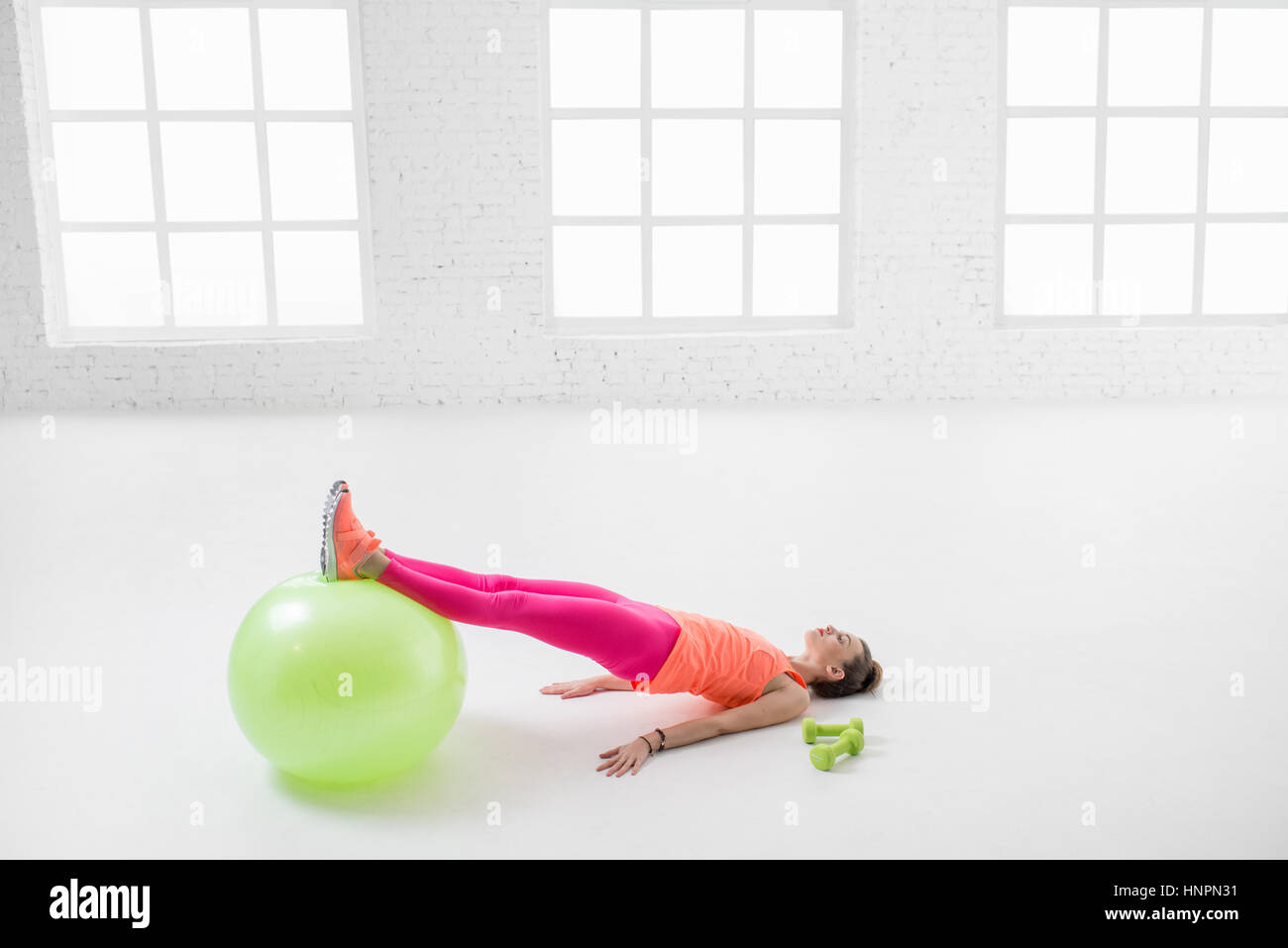 Young woman in colorful sportswear stretching with fitness ball in the ...