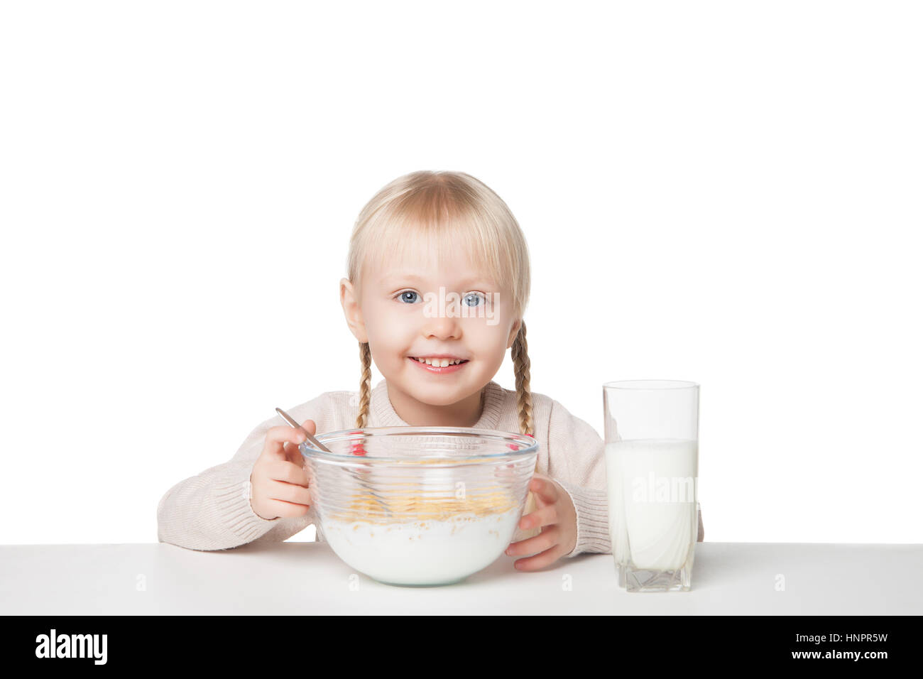 Smiling little girl eating flakes. Isolated on white background Stock ...