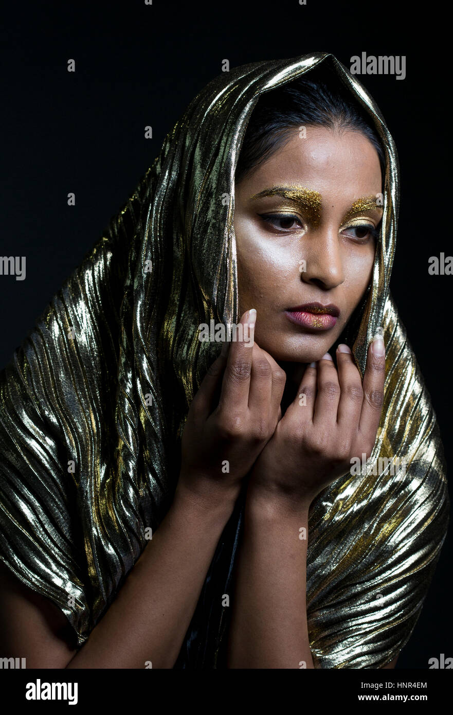 young woman dressed in gold posing for camera Stock Photo - Alamy