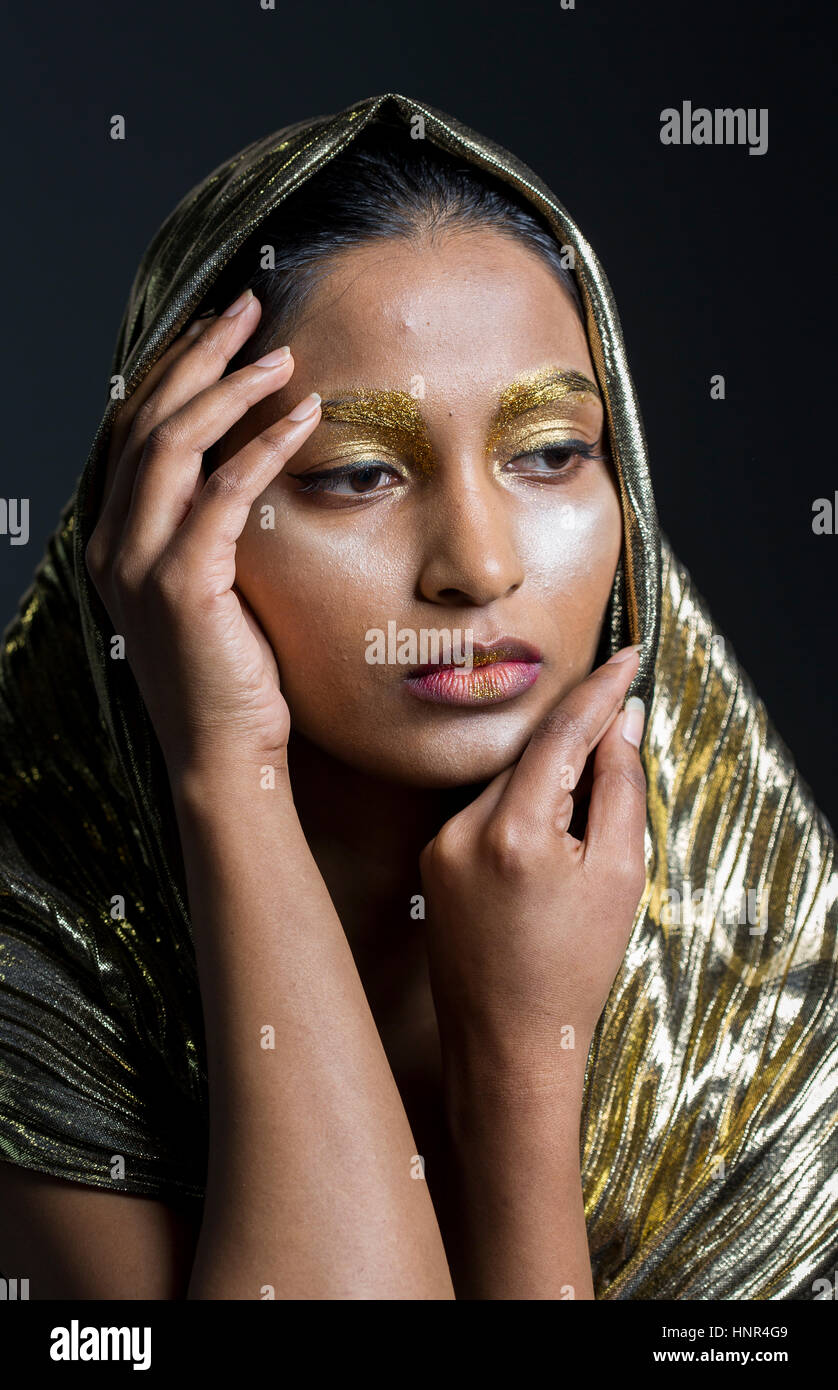 young woman dressed in gold posing for camera Stock Photo - Alamy