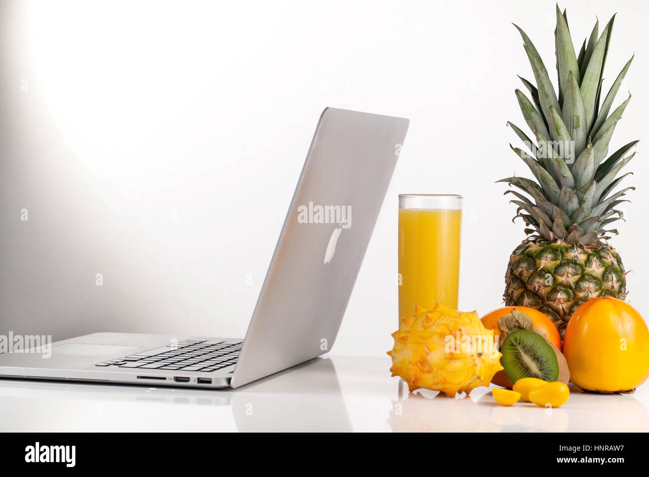Laptop computer placed near composition of tropical fruits on a white ...