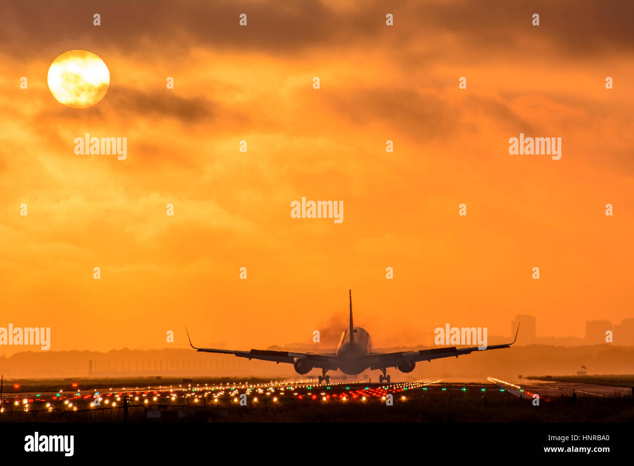 Airplane is landing during sunrise. Photo is taken on a cloudy early ...