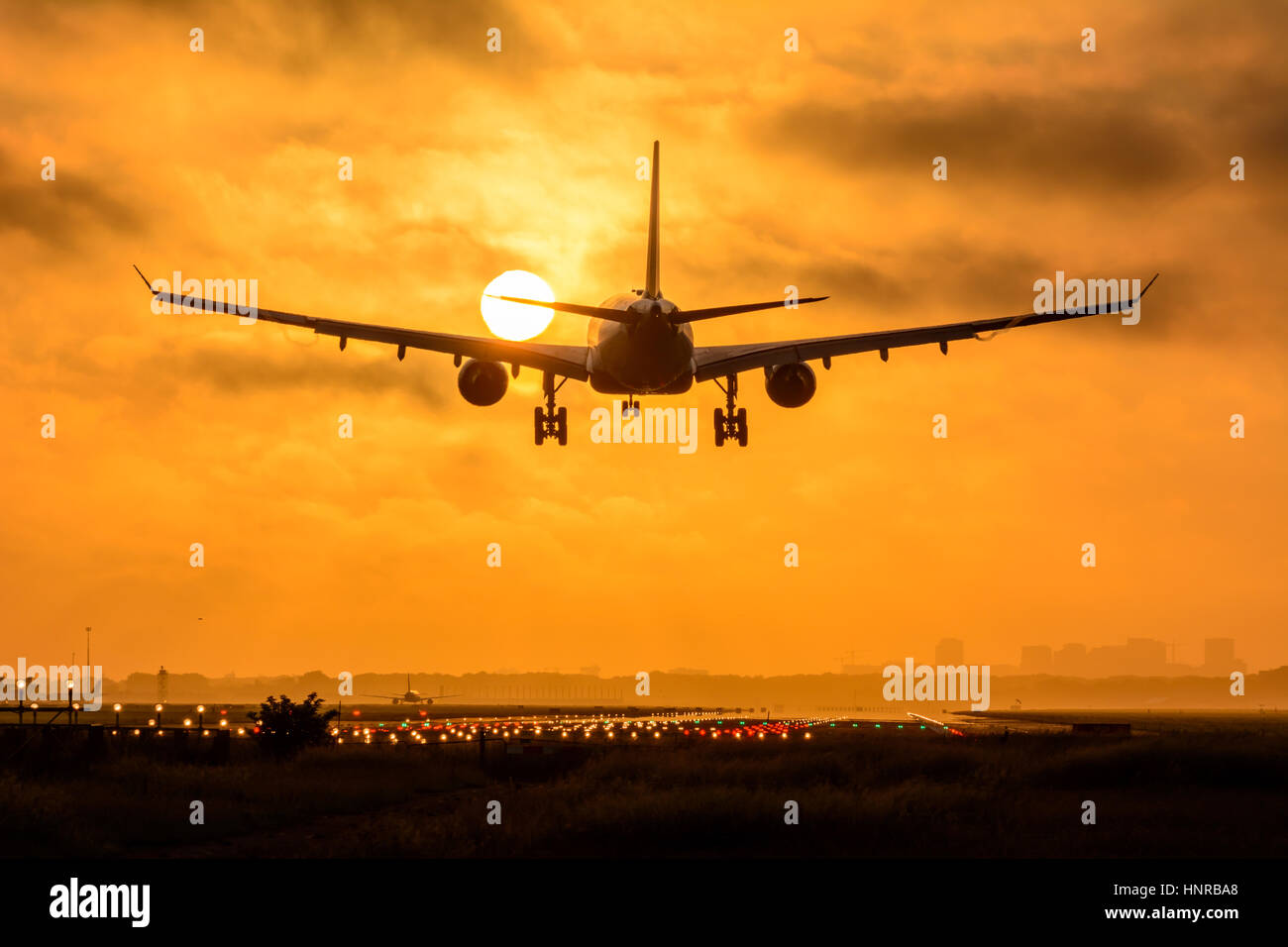 Airplane is landing during sunrise. Photo is taken on a cloudy early ...