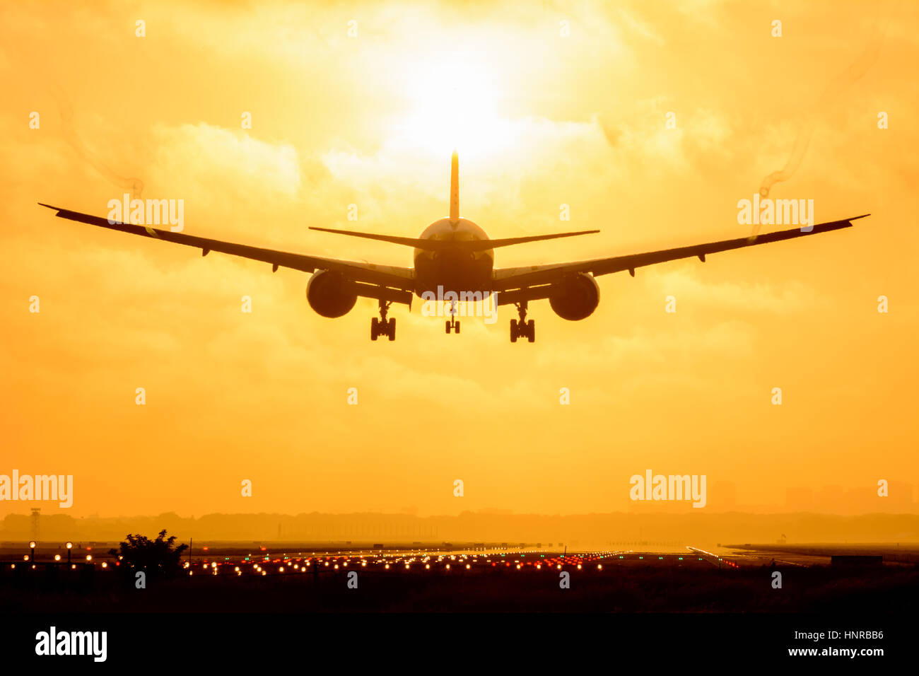 Airplane is landing during sunrise. Photo is taken on a cloudy early ...