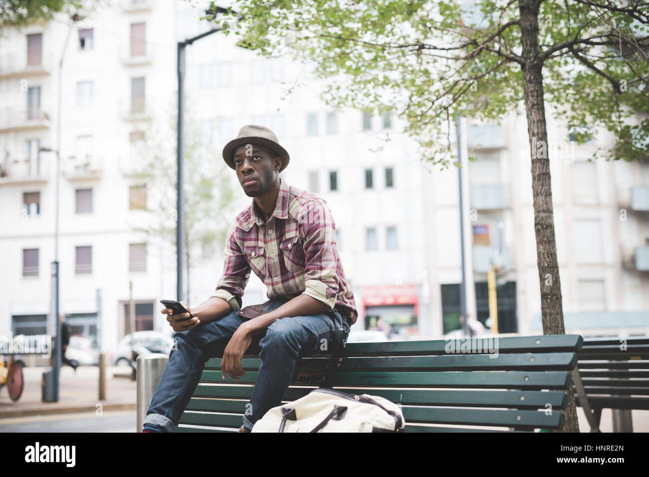 young handsome afro black man sitting on a bench holding a smartphone - technology, social ...