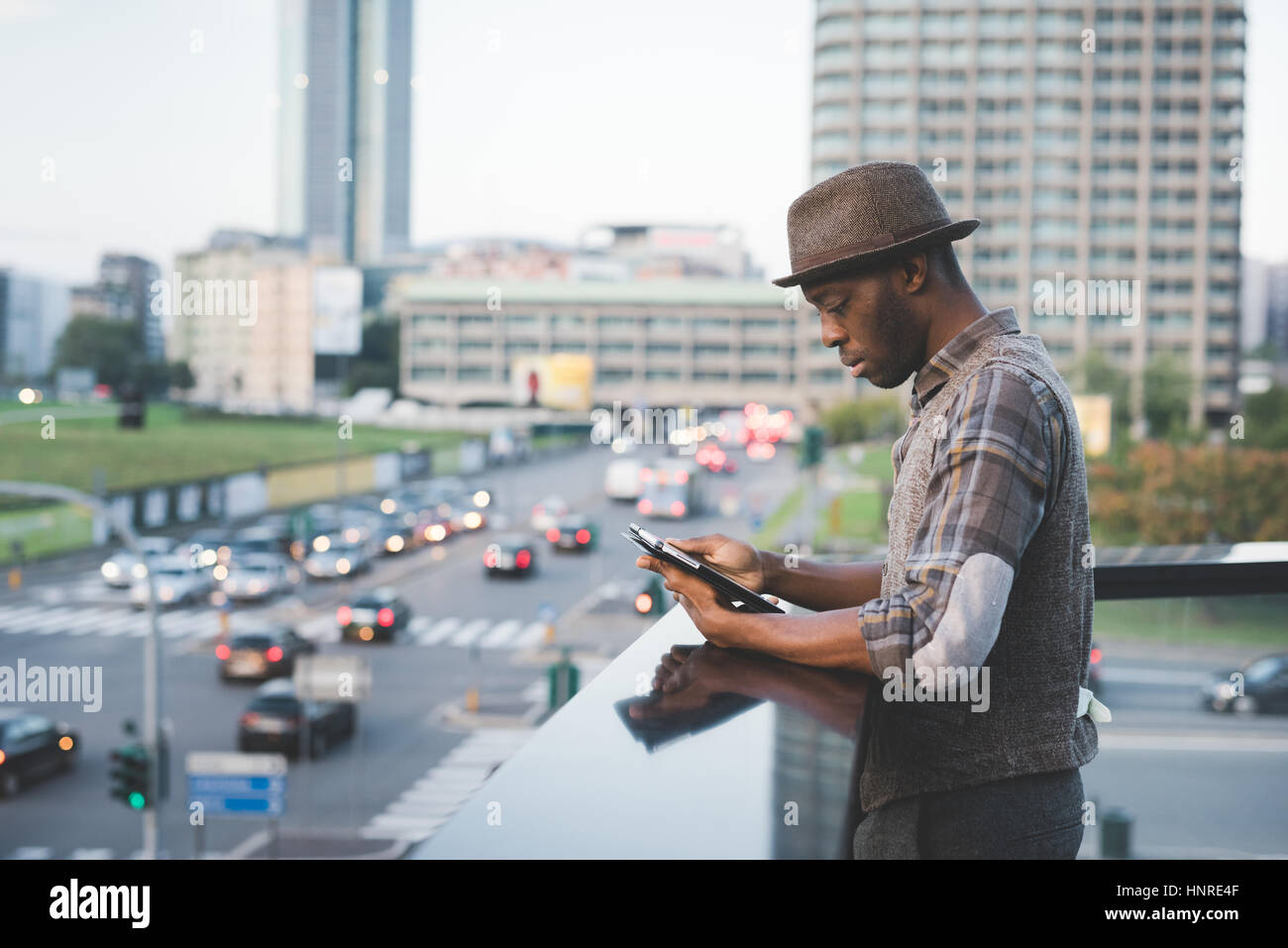 young handsome afro black man sitting on a handrail outdoorusing smart phone - technology ...