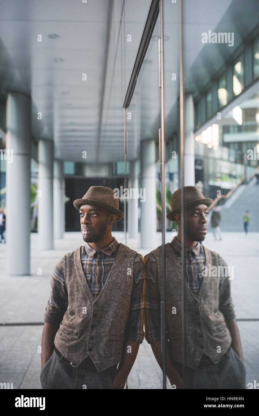 young handsome afro black man leaning against a mirrored wall ...