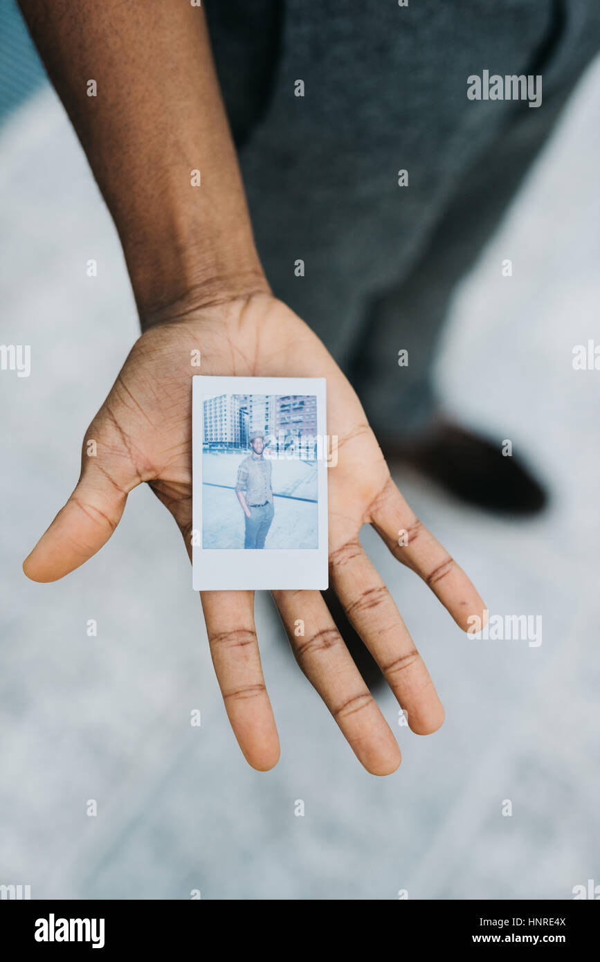 Close up on the hand of young handsome afro black man showing a photo of himself taken with ...