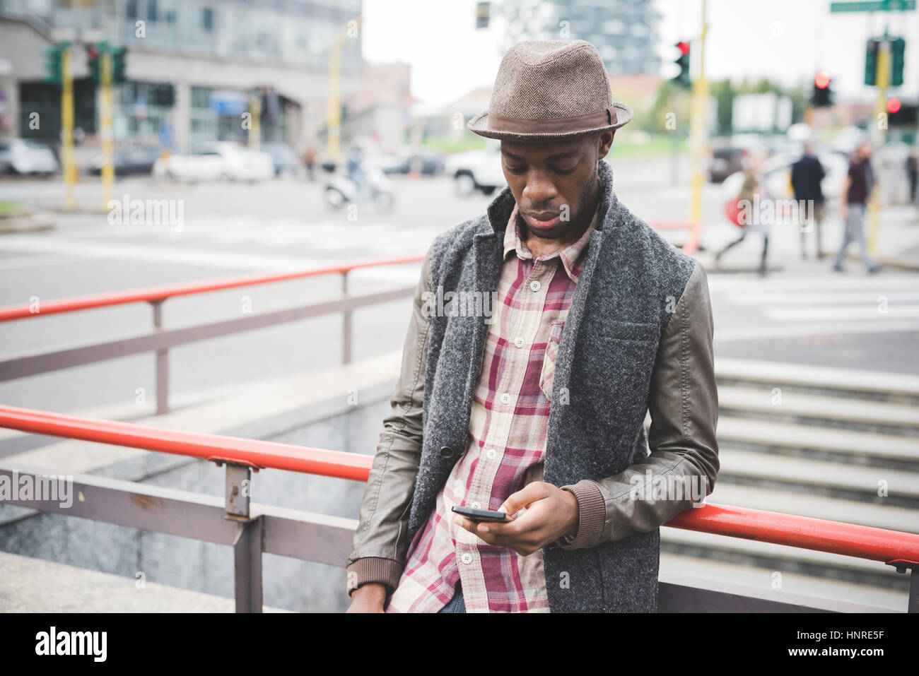 Young handsome afro black man leaning on a handrail, using smart phone hand hold - technology ...