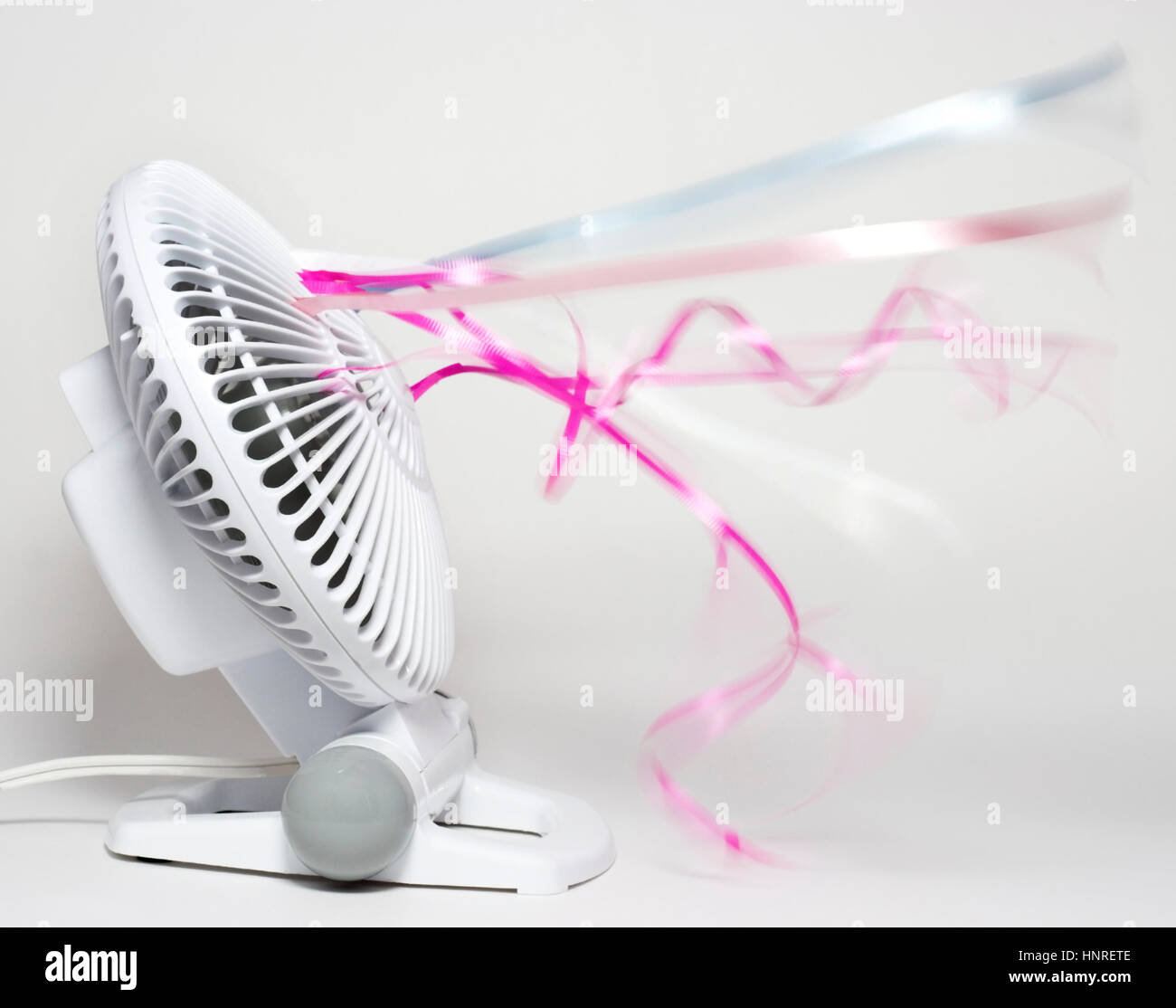 Table fan blowing colorful streamers Stock Photo - Alamy