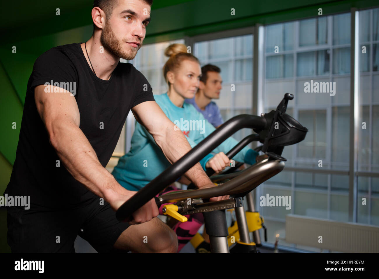 Young athletes on stationary bike at gym Stock Photo - Alamy