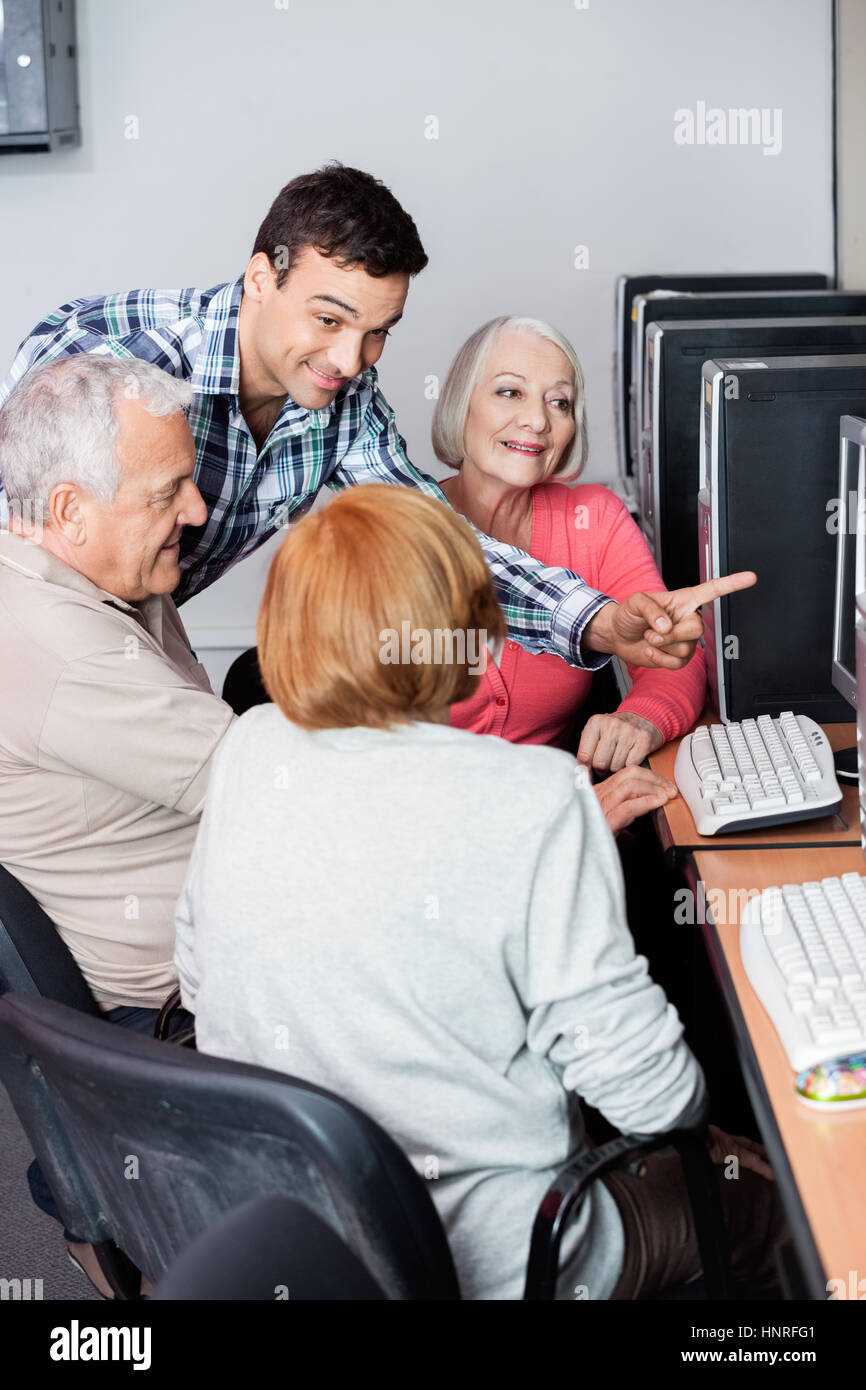 Teacher Assisting Senior People In Using Computer At Classroom Stock ...