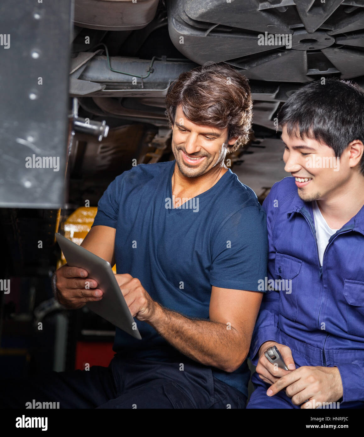 Mechanics Using Digital Tablet Under Car Stock Photo - Alamy