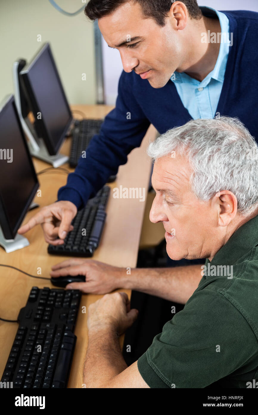 Teacher Explaining Senior Man In Computer Class Stock Photo - Alamy
