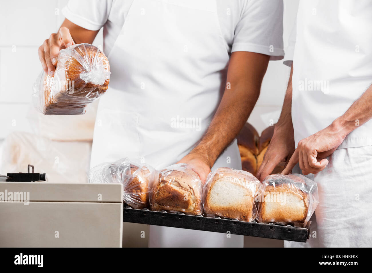 Midsection Of Baker's With Packed Bread Loaves In Bakery Stock Photo ...