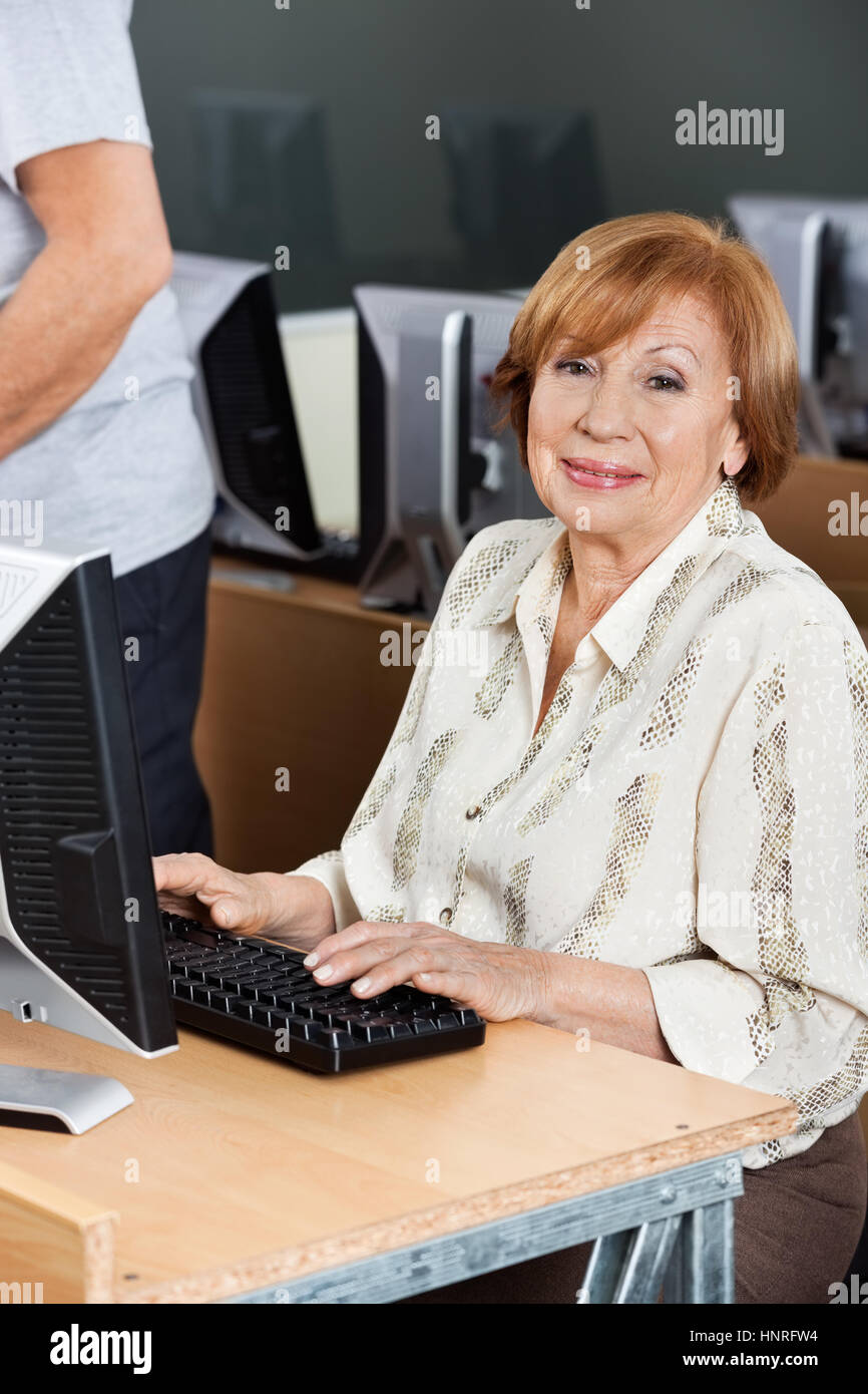 Happy Senior Woman Using Computer At Desk In Classroom Stock Photo - Alamy