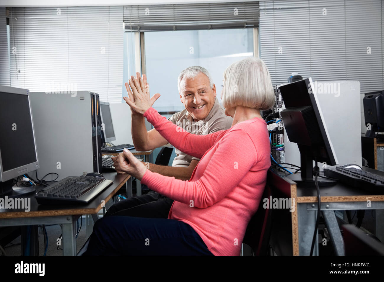 Senior People Giving High Five In Computer Class Stock Photo - Alamy