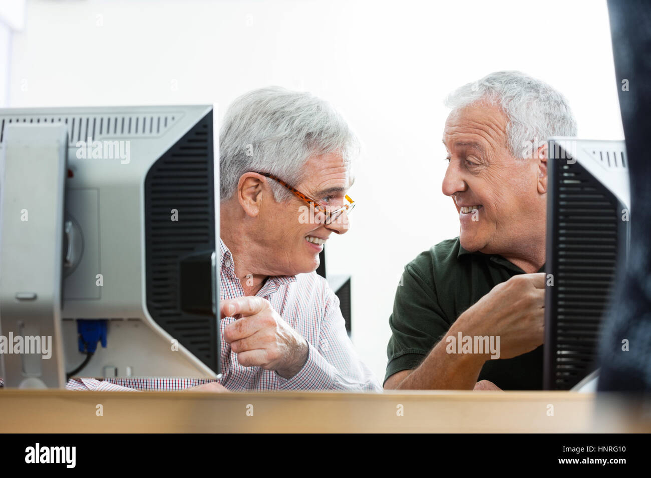 Senior Classmates Talking At Computer Desk In Classroom Stock Photo - Alamy
