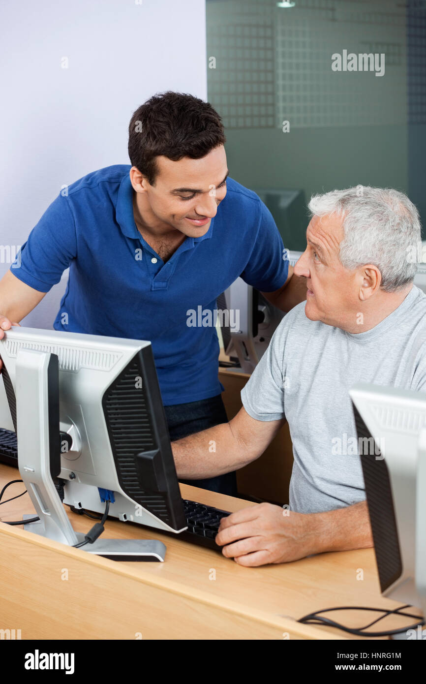 Teacher Looking At Senior Man Using Computer Classroom Stock Photo - Alamy