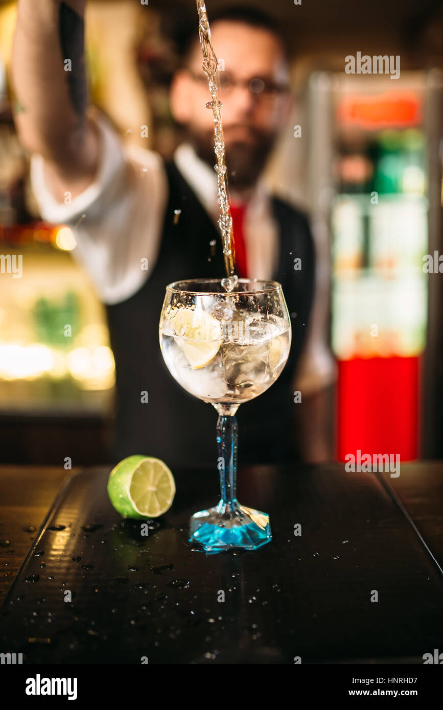 Bartender pouring alcoholic drink in glass. Barman flairing with ...