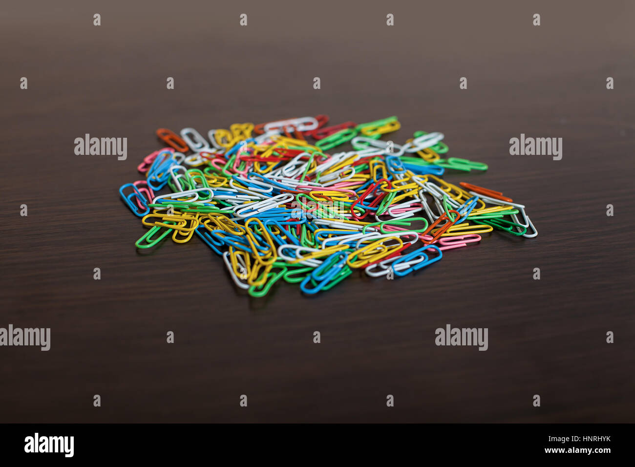 Colorful paper clips isolated on wooden background. Office color ...