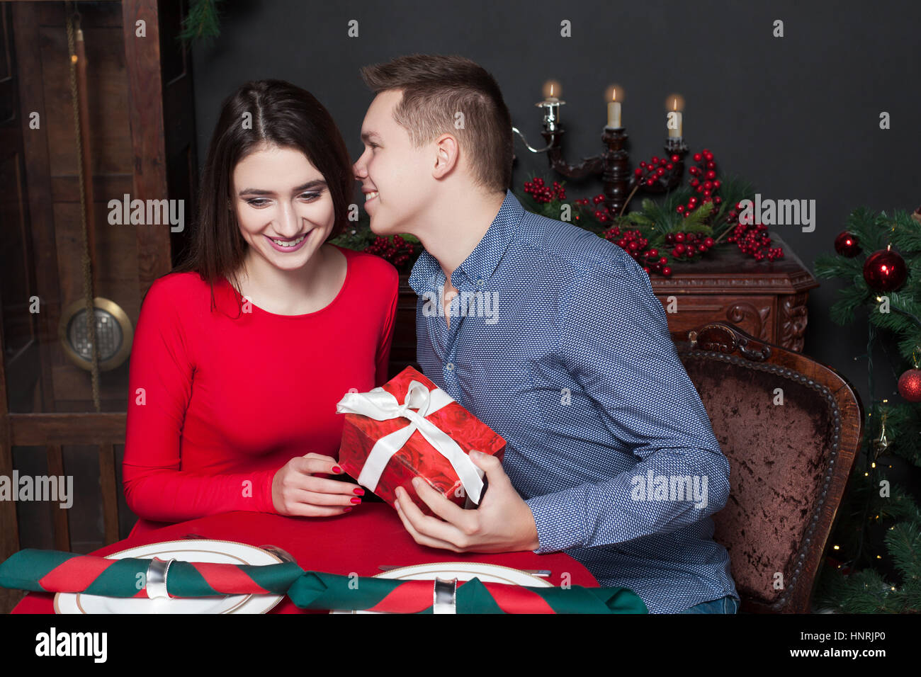 Young man gives a gift to beautiful woman. Love couple at luxury ...