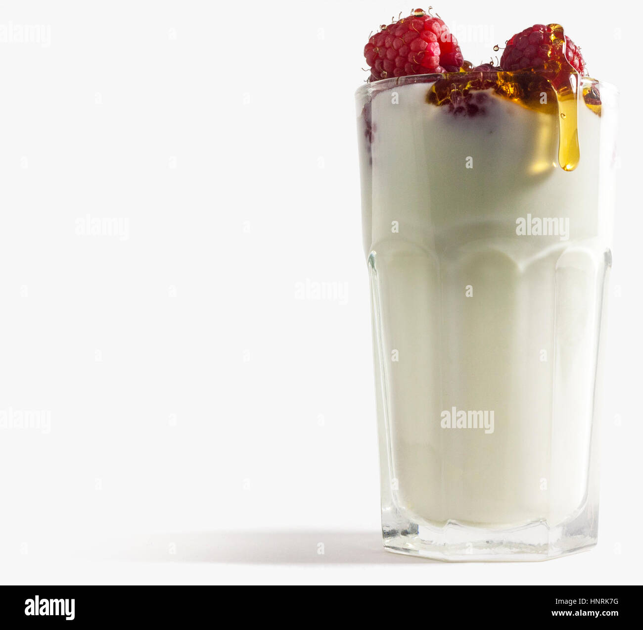 A glass of yogurt with red raspberries and honey Stock Photo - Alamy