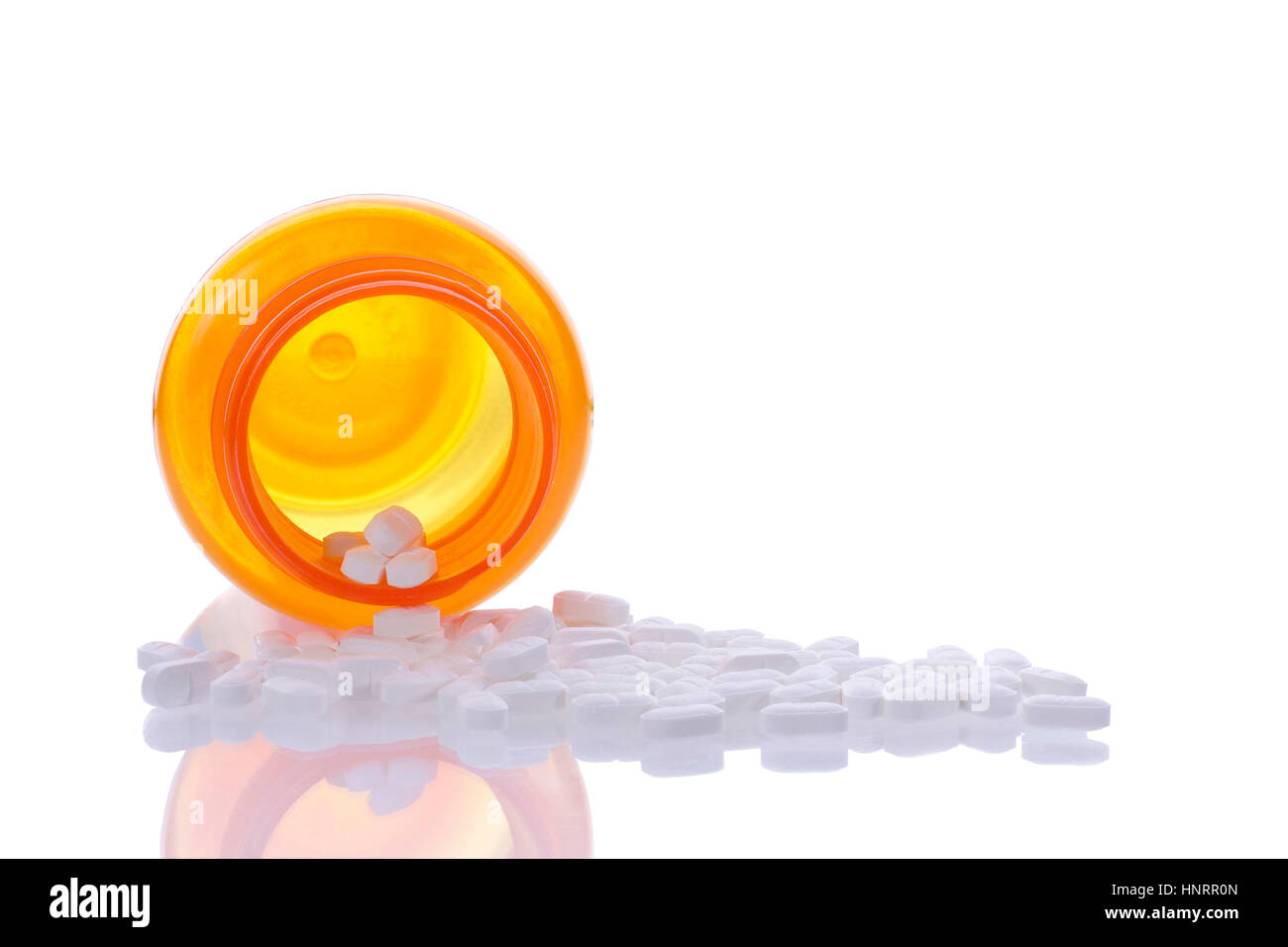 medication bottle on side with pills spilling out onto a reflective ...