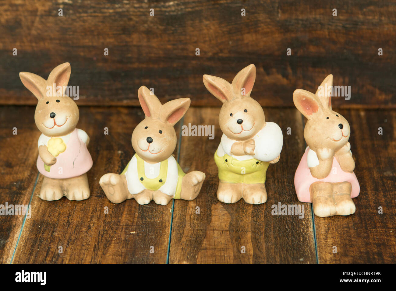 Four ceramic painted rabbits for Easter decoration on a wooden ...