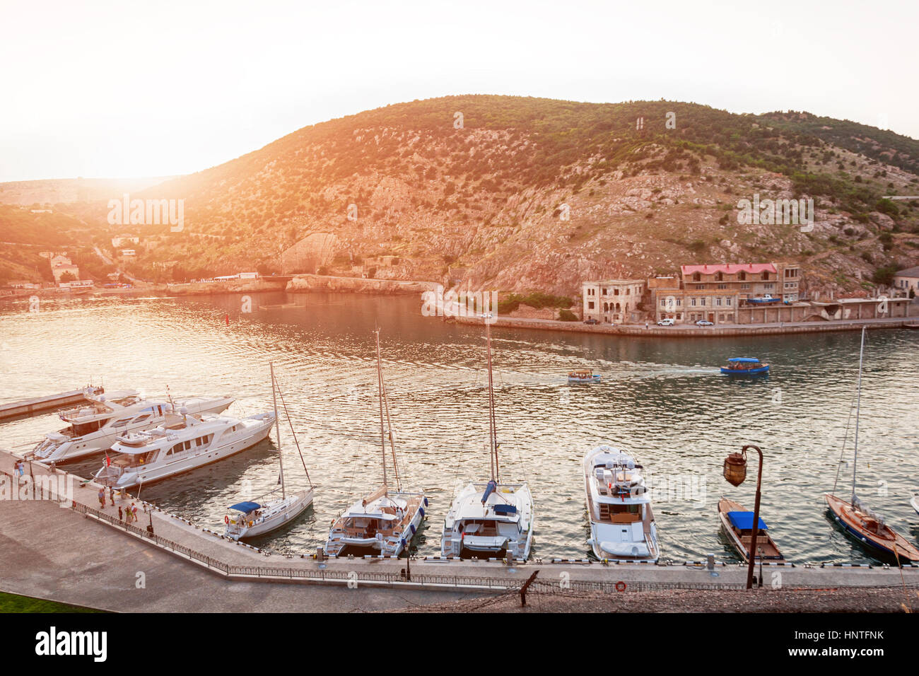 Sailing boats and yachts anchored in calm bay at sunset Stock Photo - Alamy