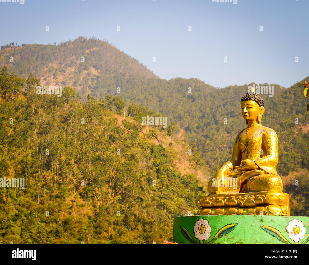 Golden Statue of Budhda with background of green forest and blue sky ...