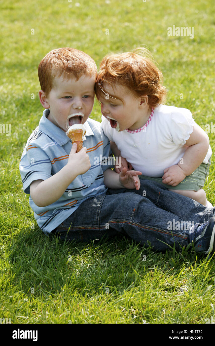 Two children sharing an ice cream in a park Stock Photo - Alamy