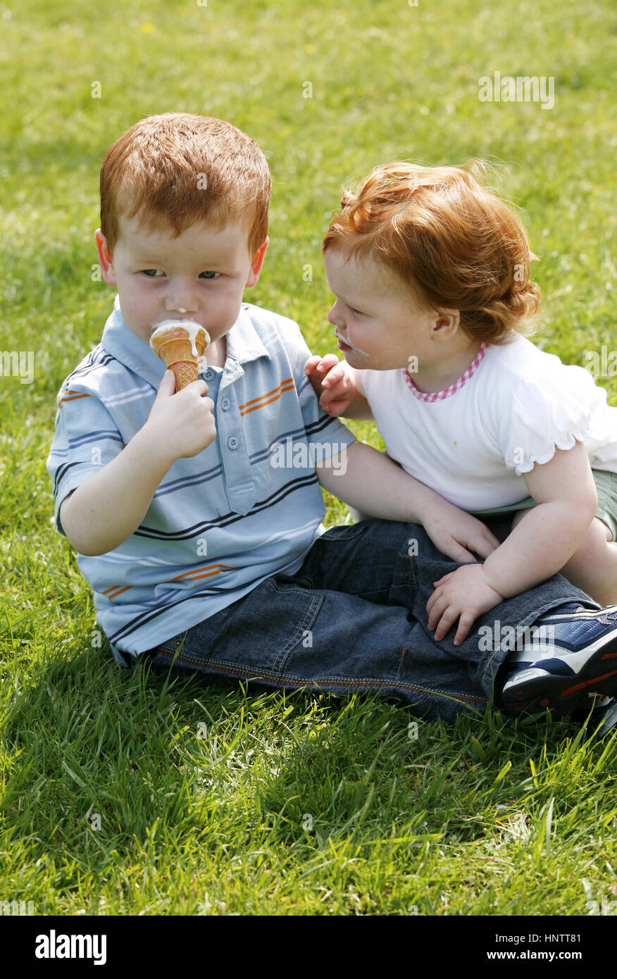 Two children sharing an ice cream in a park Stock Photo - Alamy