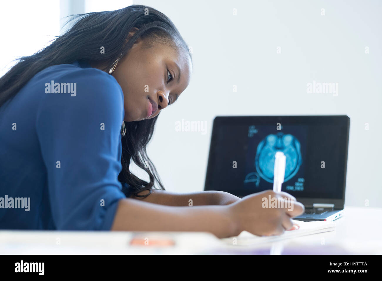 A female student studying using a laptop and text books Stock Photo - Alamy