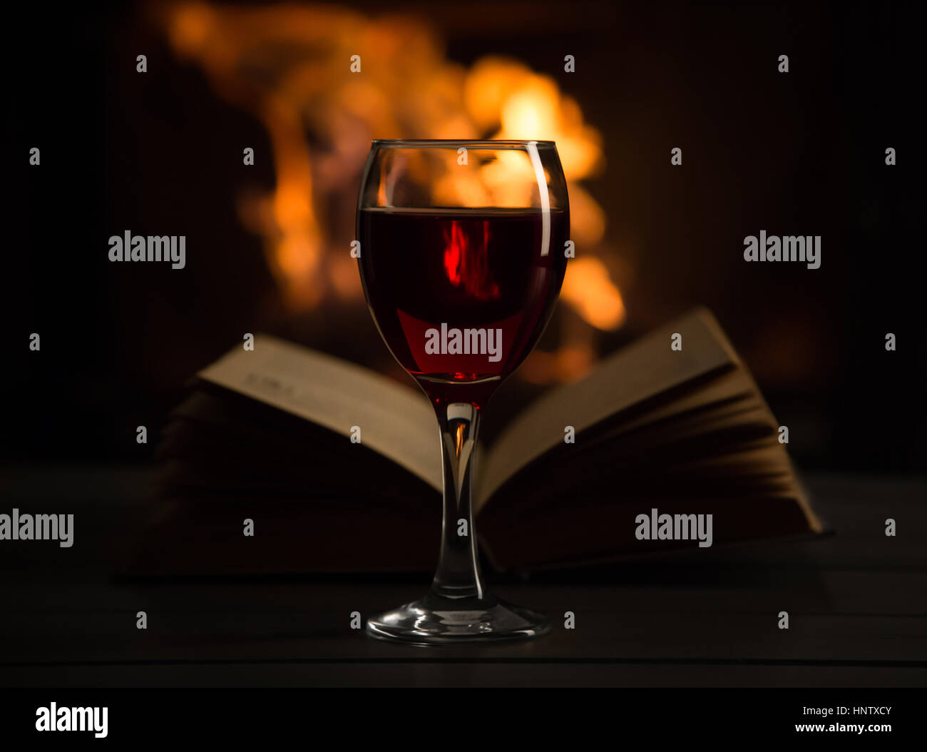 Open book with red wine in front of the fireplace Stock Photo - Alamy