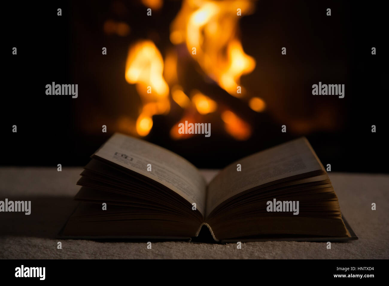 Open book in front of fireplace Stock Photo - Alamy