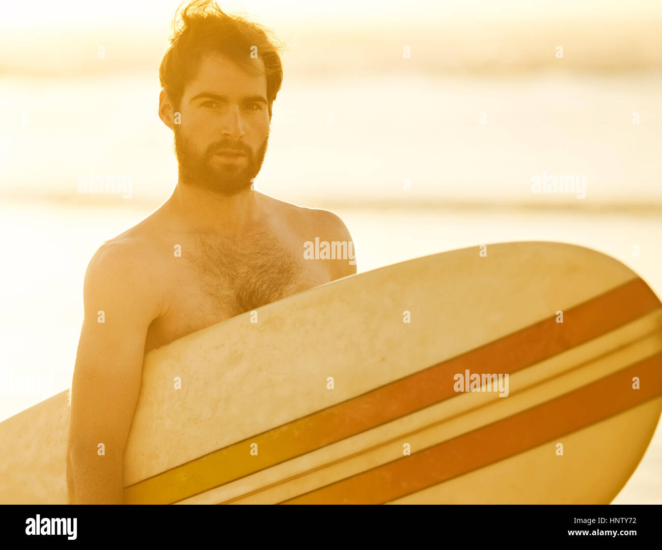 Handsome bearded surfer holding a retro surfboard under his arm Stock ...