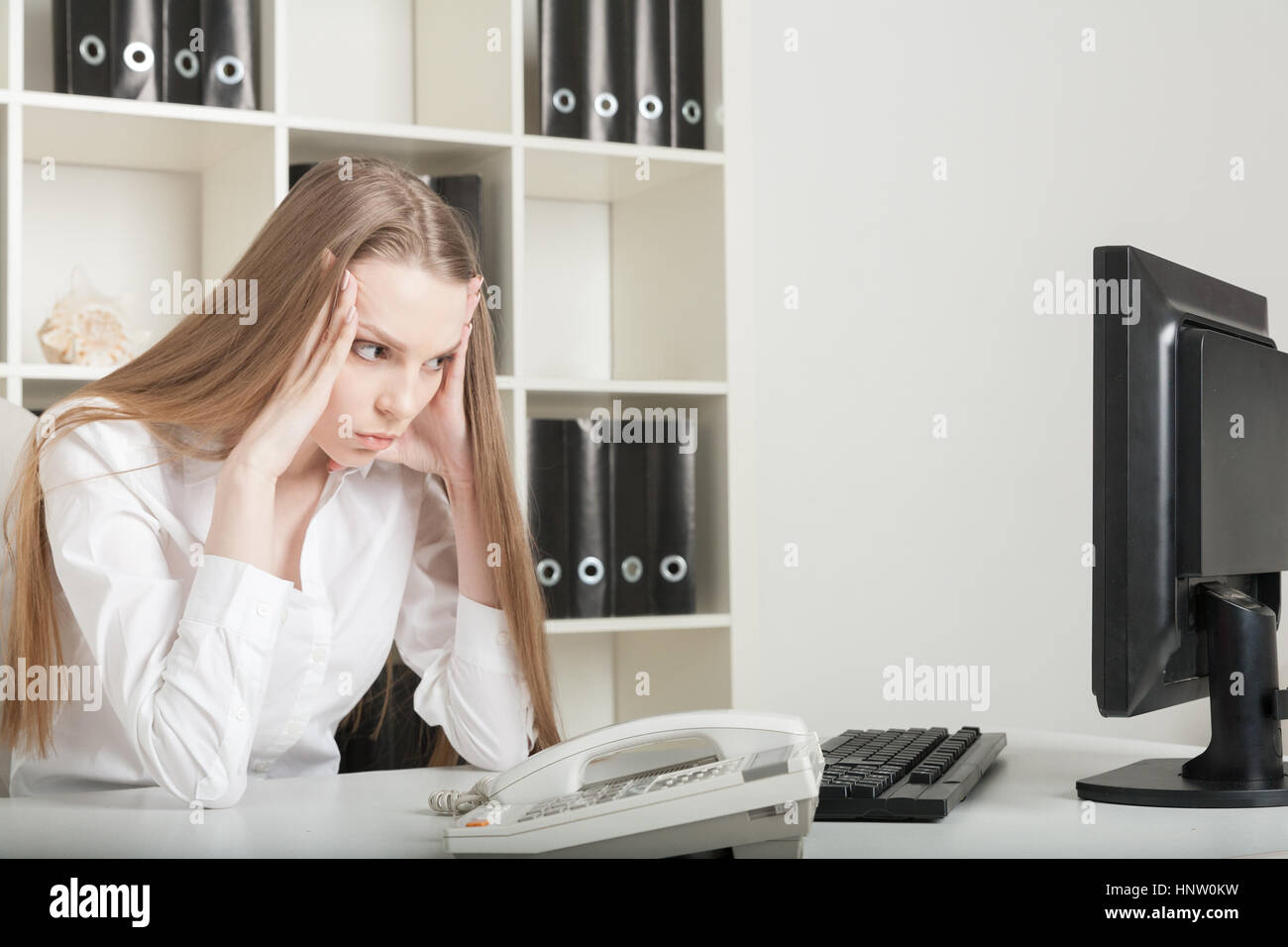 the young beautiful long-haired girl sits tired at office in the ...
