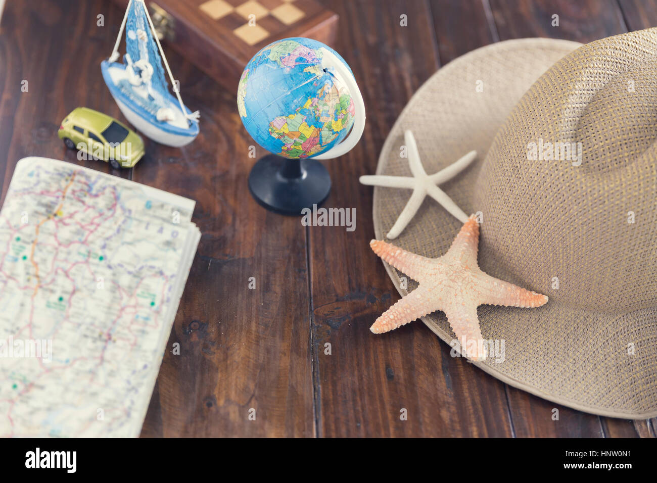 globe, hat, map, car ship and starfish figurine on wooden table for use ...
