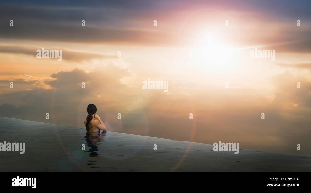 Chinese woman in infinity pool admiring sunset Stock Photo - Alamy