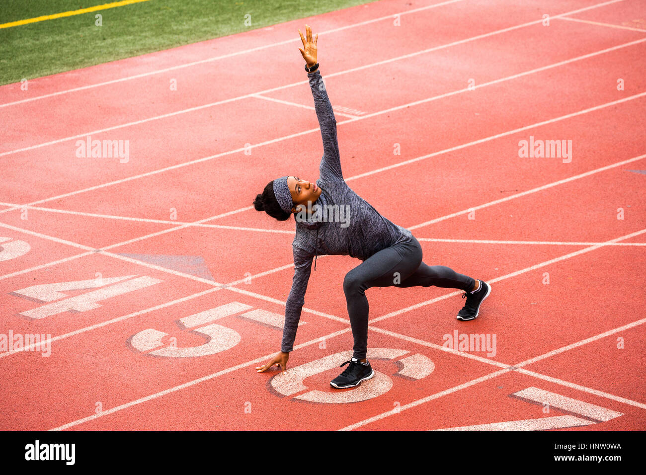 Black woman stretching on track starting line Stock Photo - Alamy
