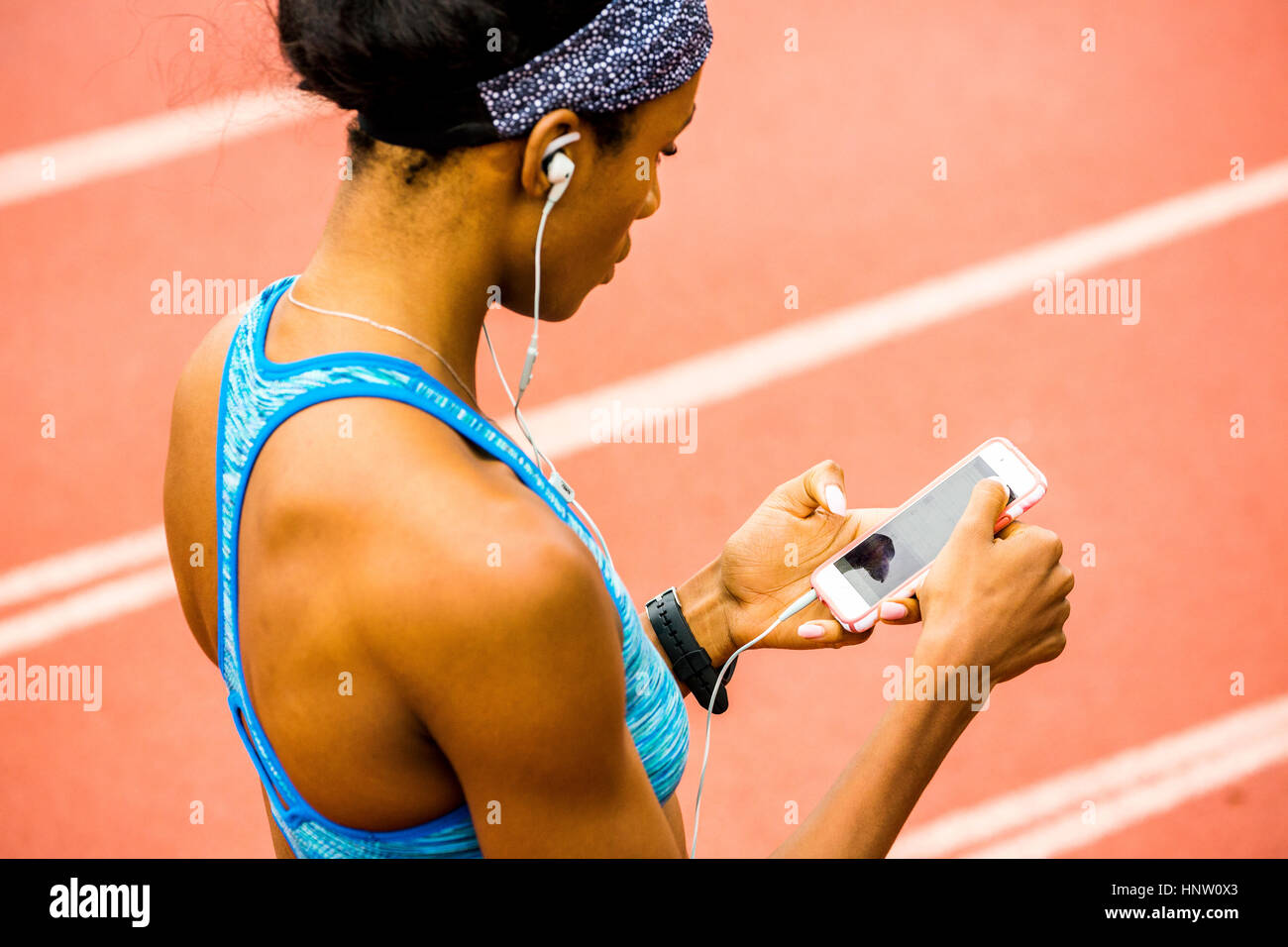Black woman on track listening to cell phone with earbuds Stock Photo ...