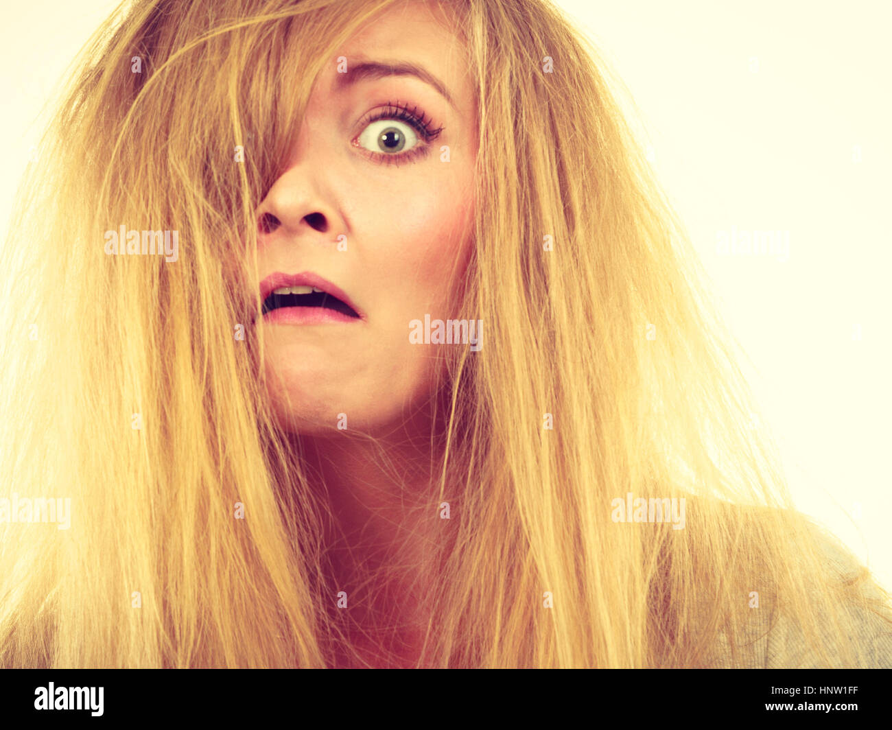 Bad hairstyle concept. Crazy, mad blonde woman with messy hair looking ...