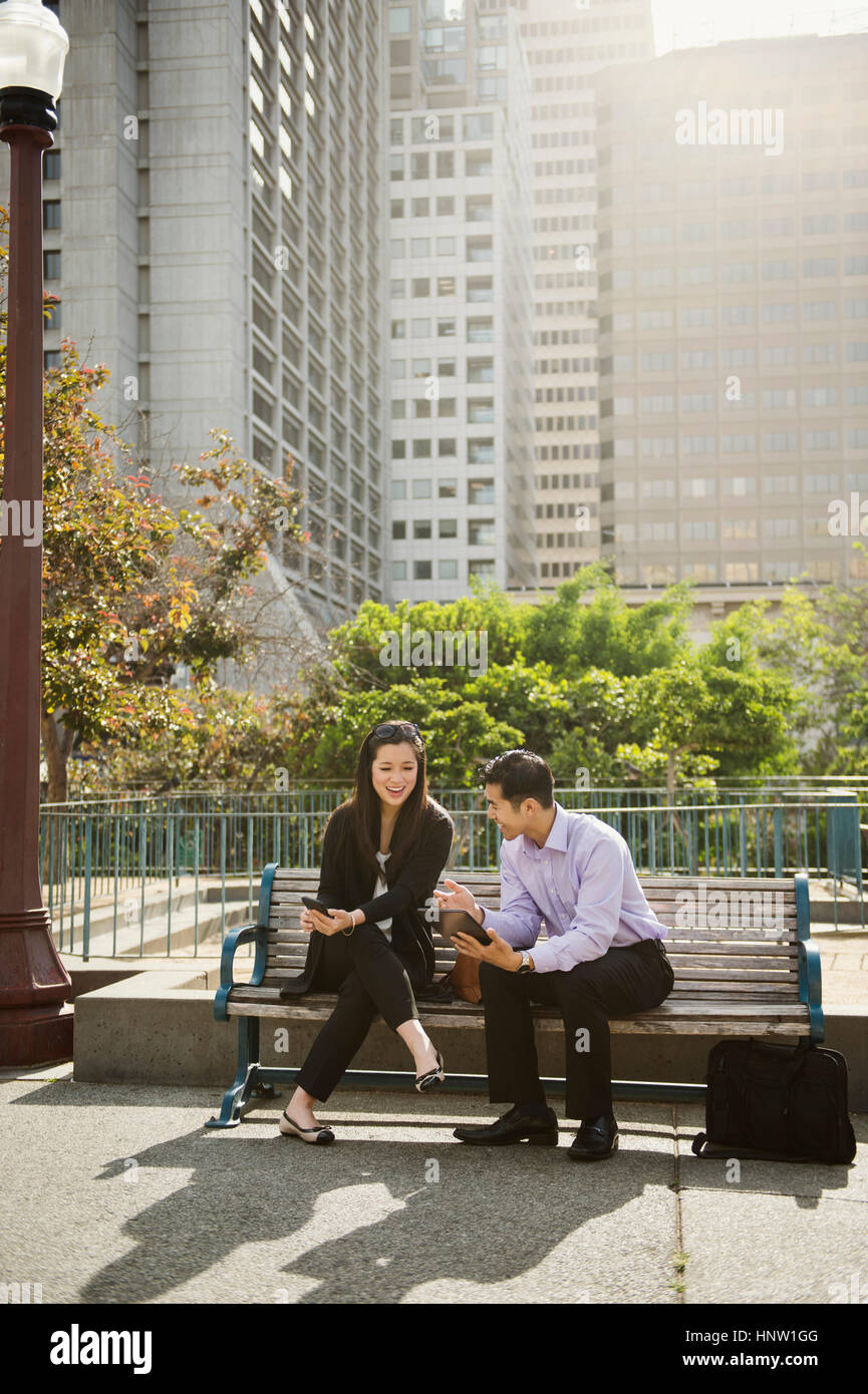 Chinese business people using technology on city bench Stock Photo - Alamy