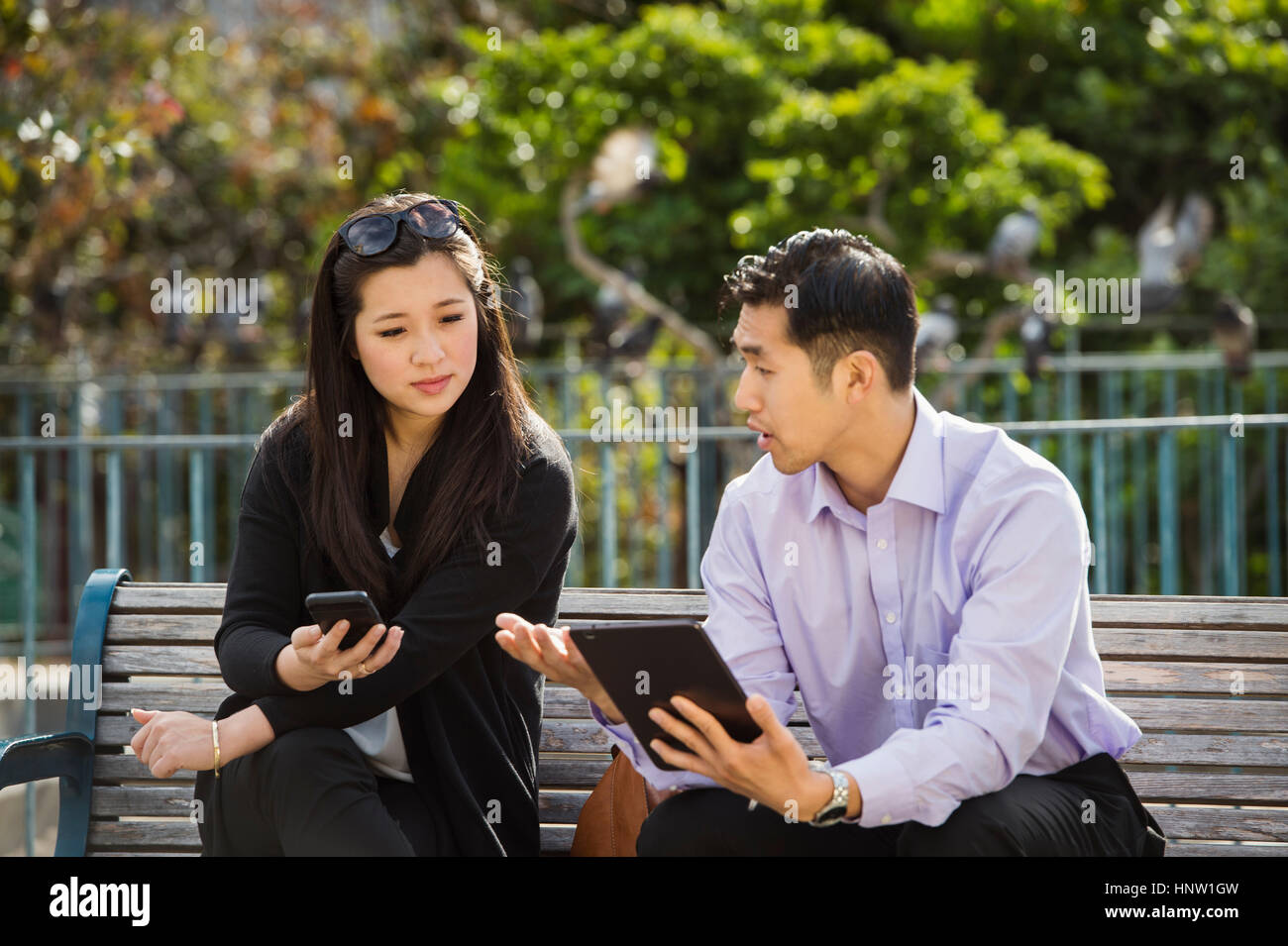 Chinese business people using technology on city bench Stock Photo - Alamy