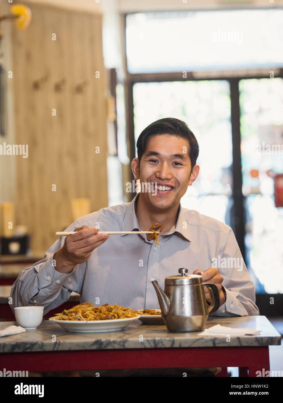 Chinese man eating with chopsticks in restaurant Stock Photo - Alamy